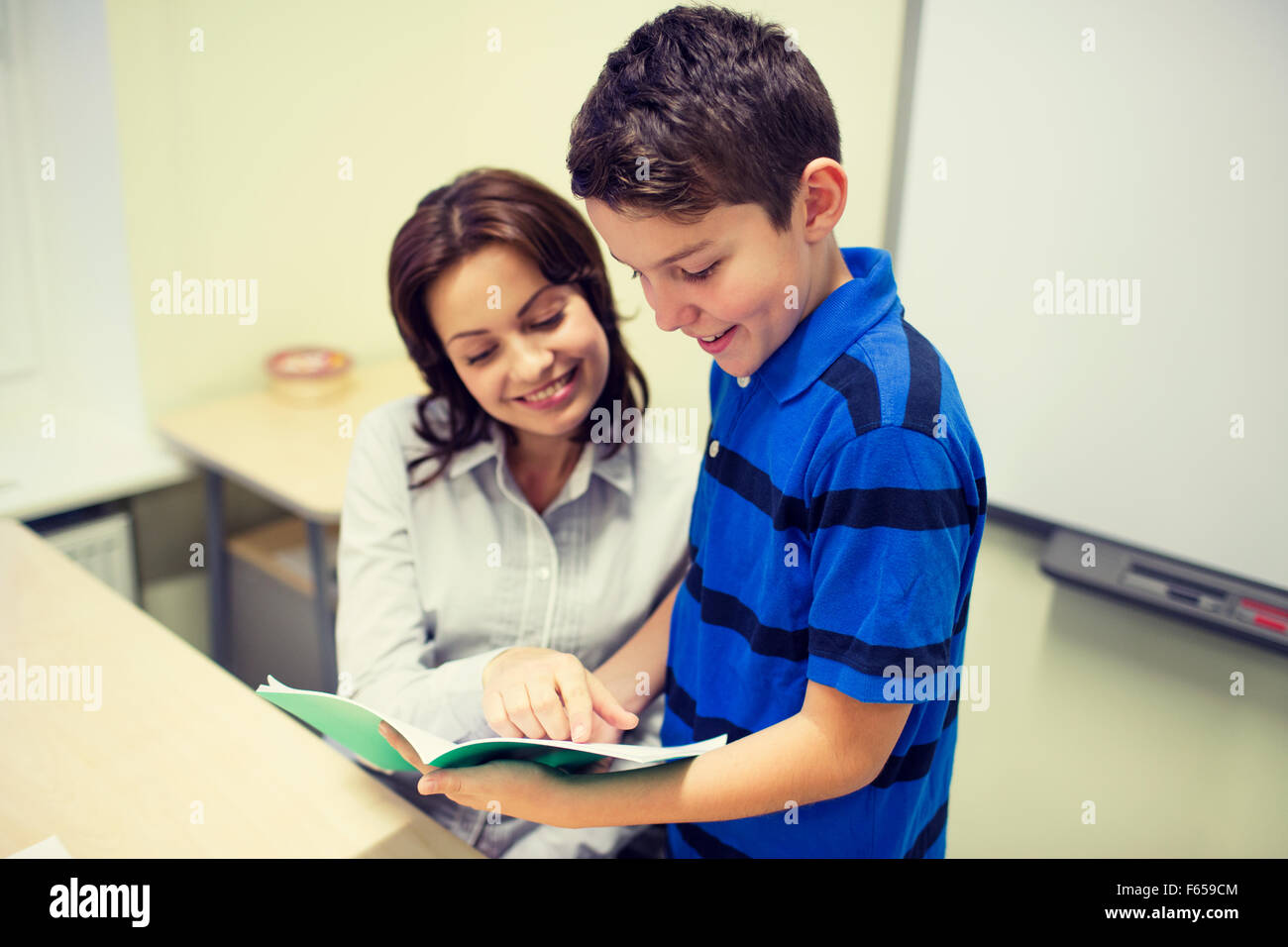 school boy with notebook and teacher in classroom Stock Photo - Alamy