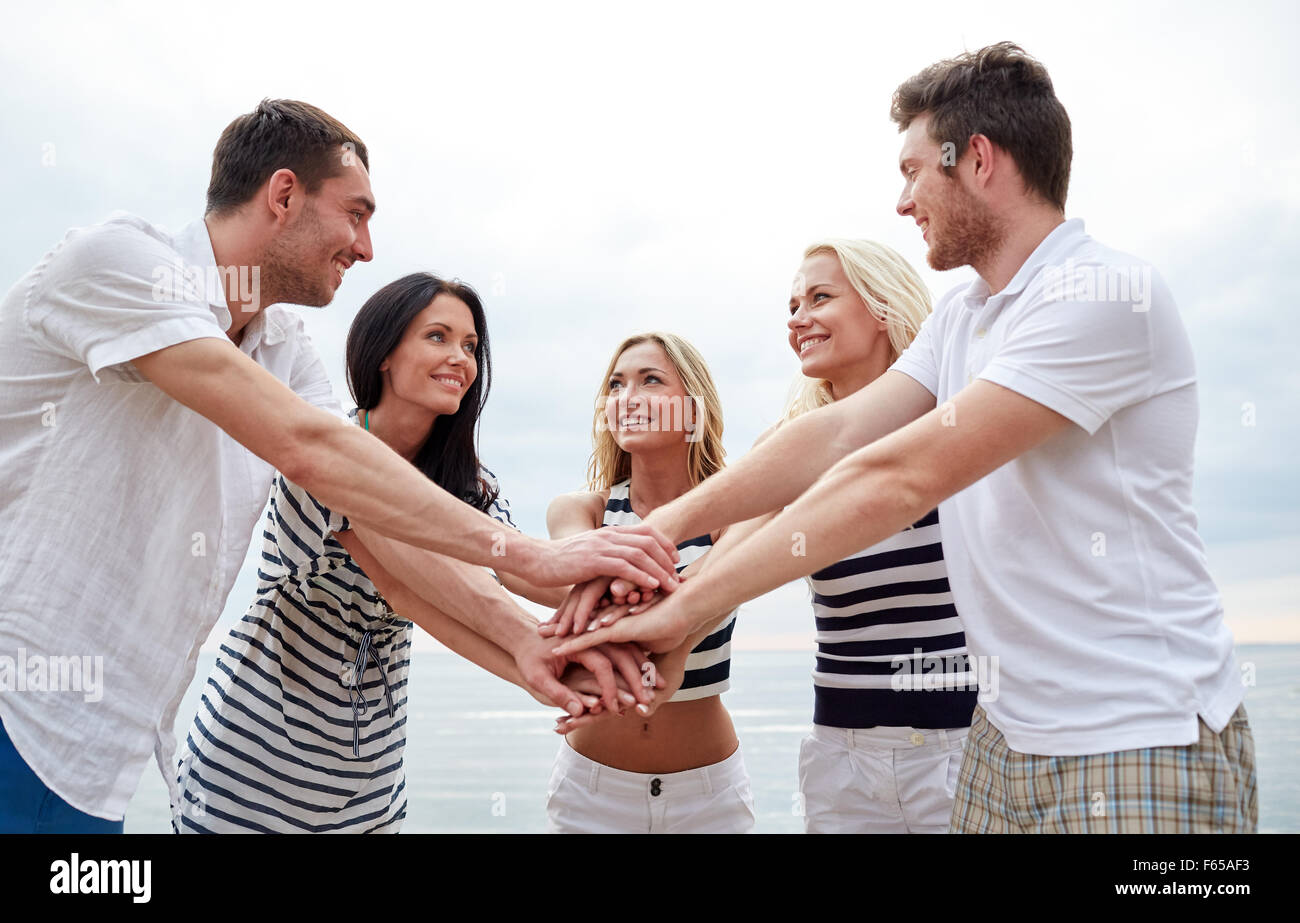smiling friends putting hands on top of each other Stock Photo - Alamy