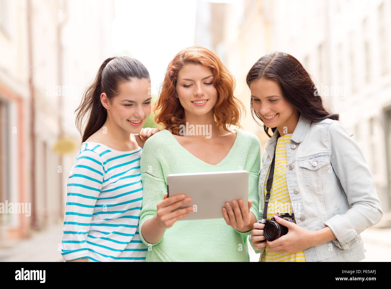 smiling teenage girls with tablet pc and camera Stock Photo - Alamy