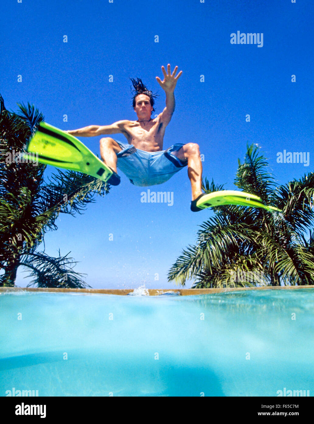 Carefree man wearing flippers jumping in swimming pool, low angle view ...