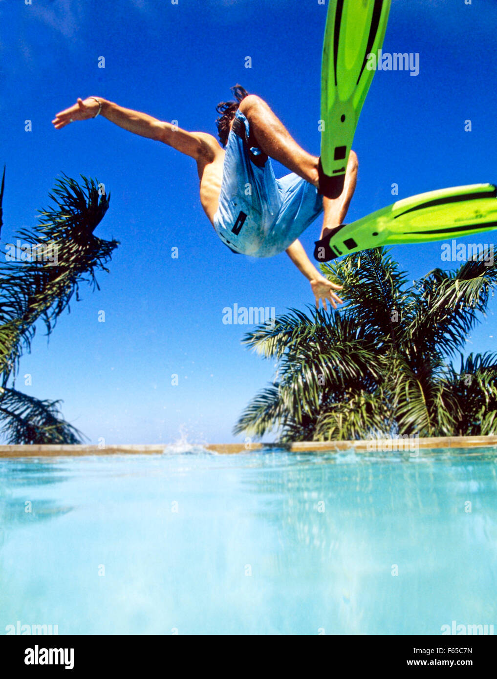Carefree man wearing flippers jumping in swimming pool, low angle view ...