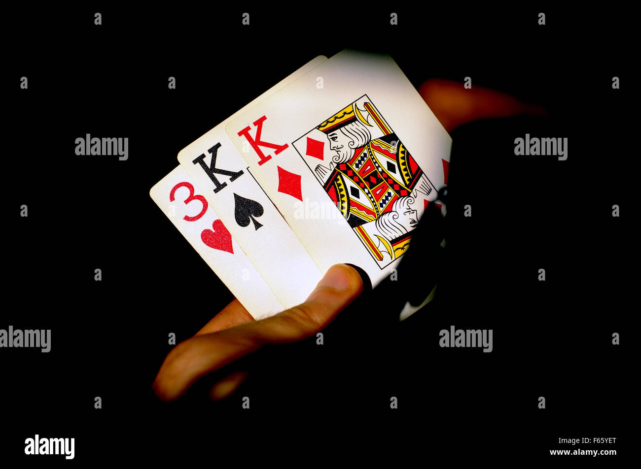 A hand holds three playing cards during a card game Stock Photo - Alamy