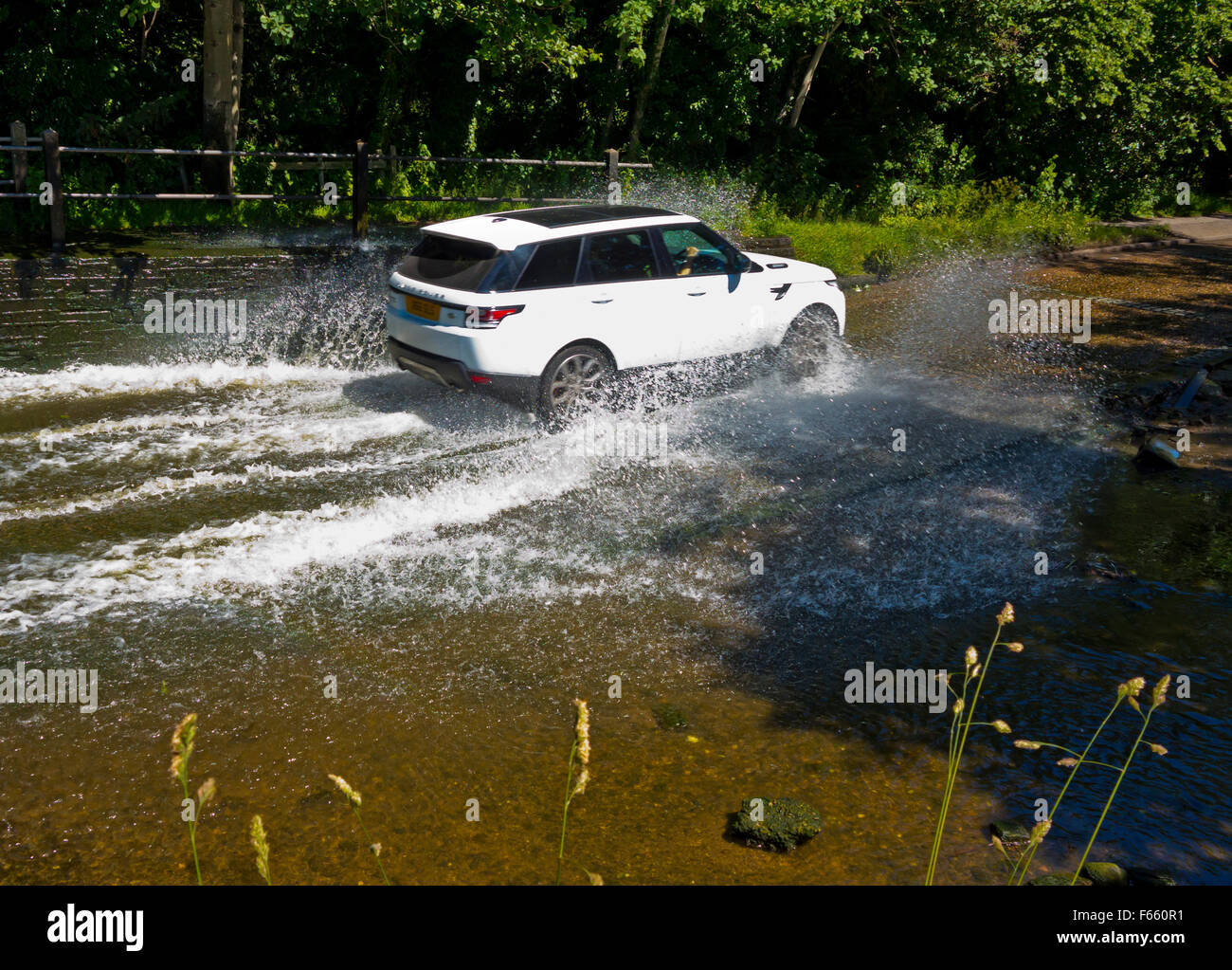 Car driving through a water filled ford crossing a stream on a country ...