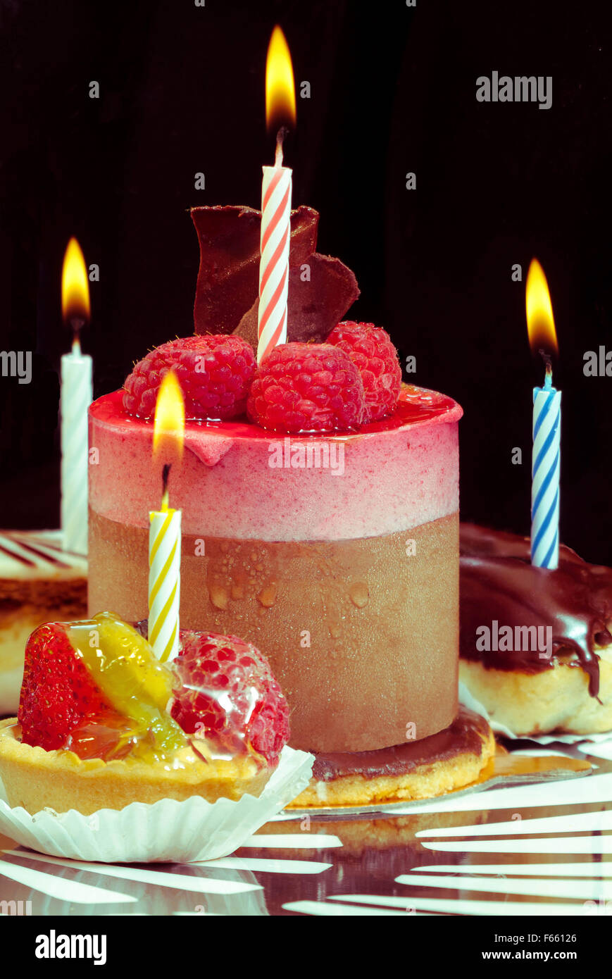 Glistening drops on pastries with lit candles on shinly black and white ...