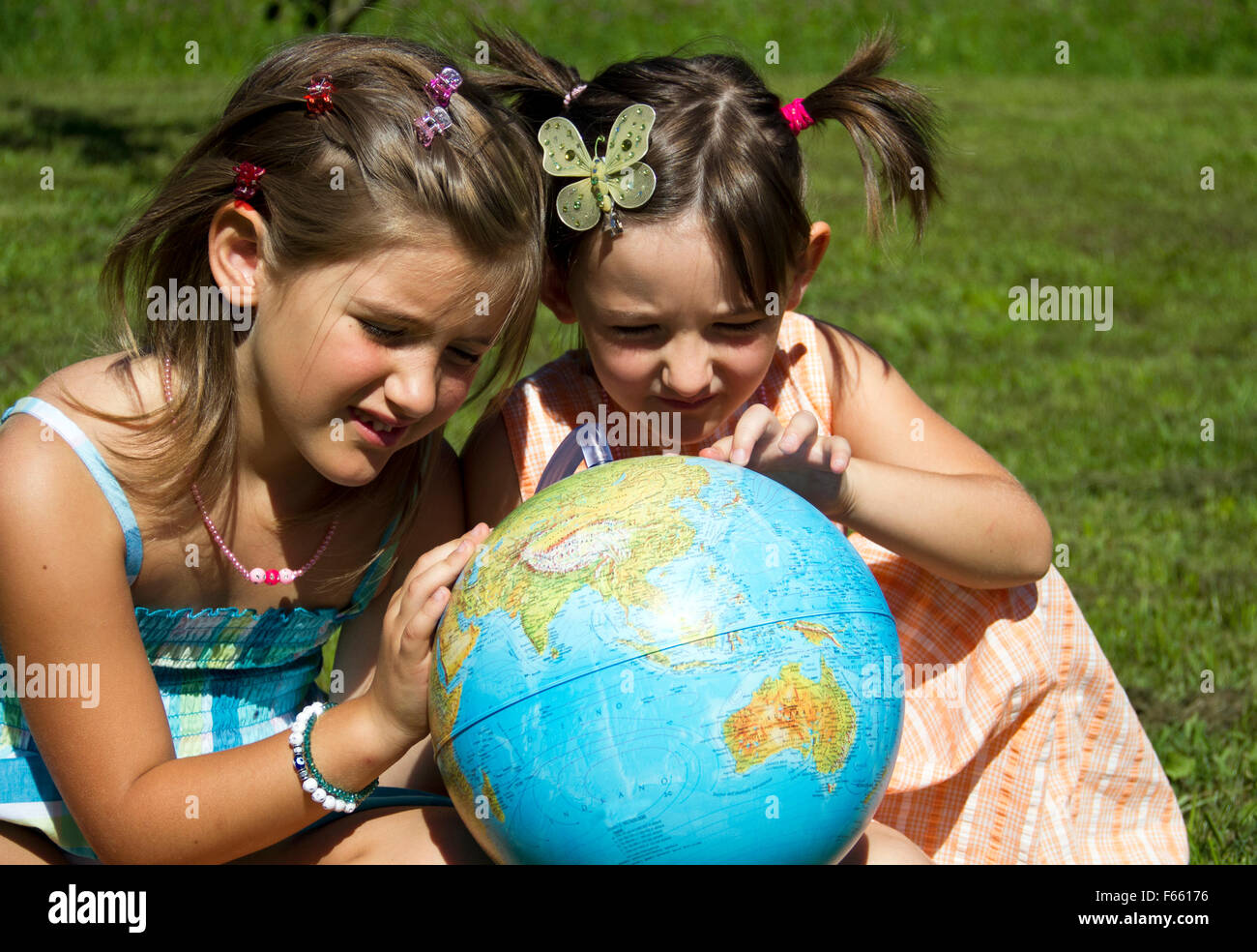 Girls looking the earth globe Stock Photo - Alamy