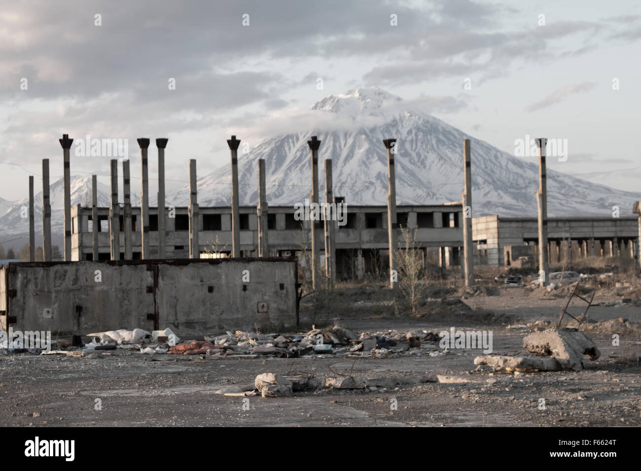 Environment pollution. Factory ruins against a picturesque volcano ...