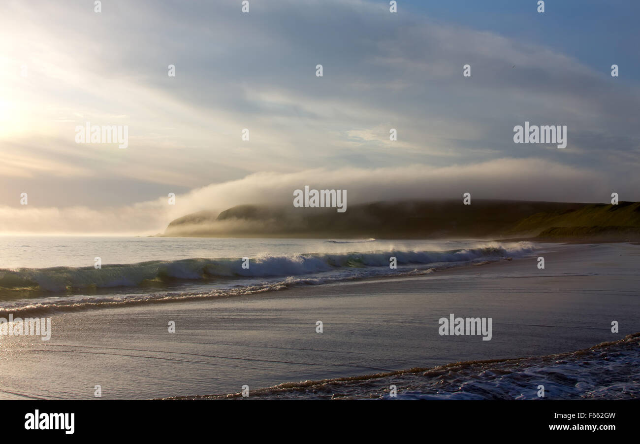 Solar ocean coast, beach, fog slipping from mountains Stock Photo - Alamy