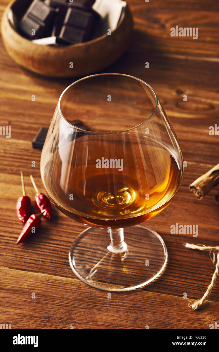 Glass of brandy on a old wooden table with a bowl with chocolate ...