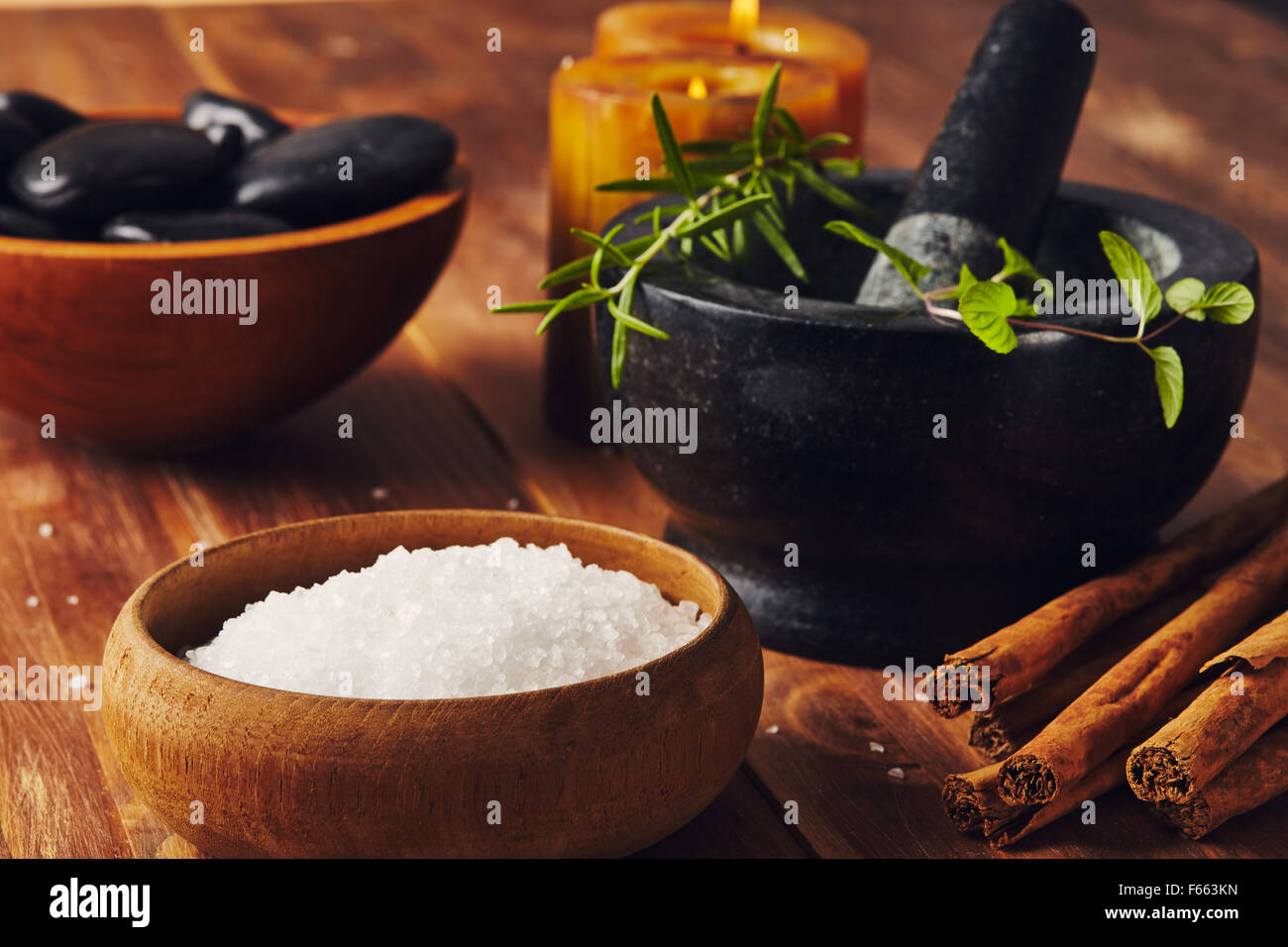 Spa tools, bath salt, mortar with herbs, a bowl with hot stones and ...