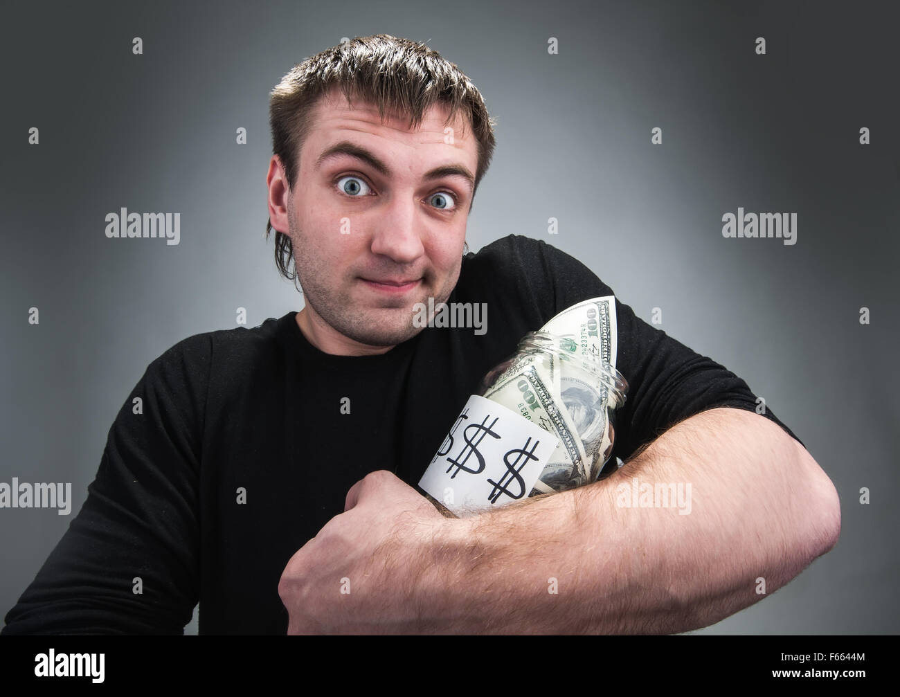 Strange man stands with jar full of dollars over grey Stock Photo - Alamy