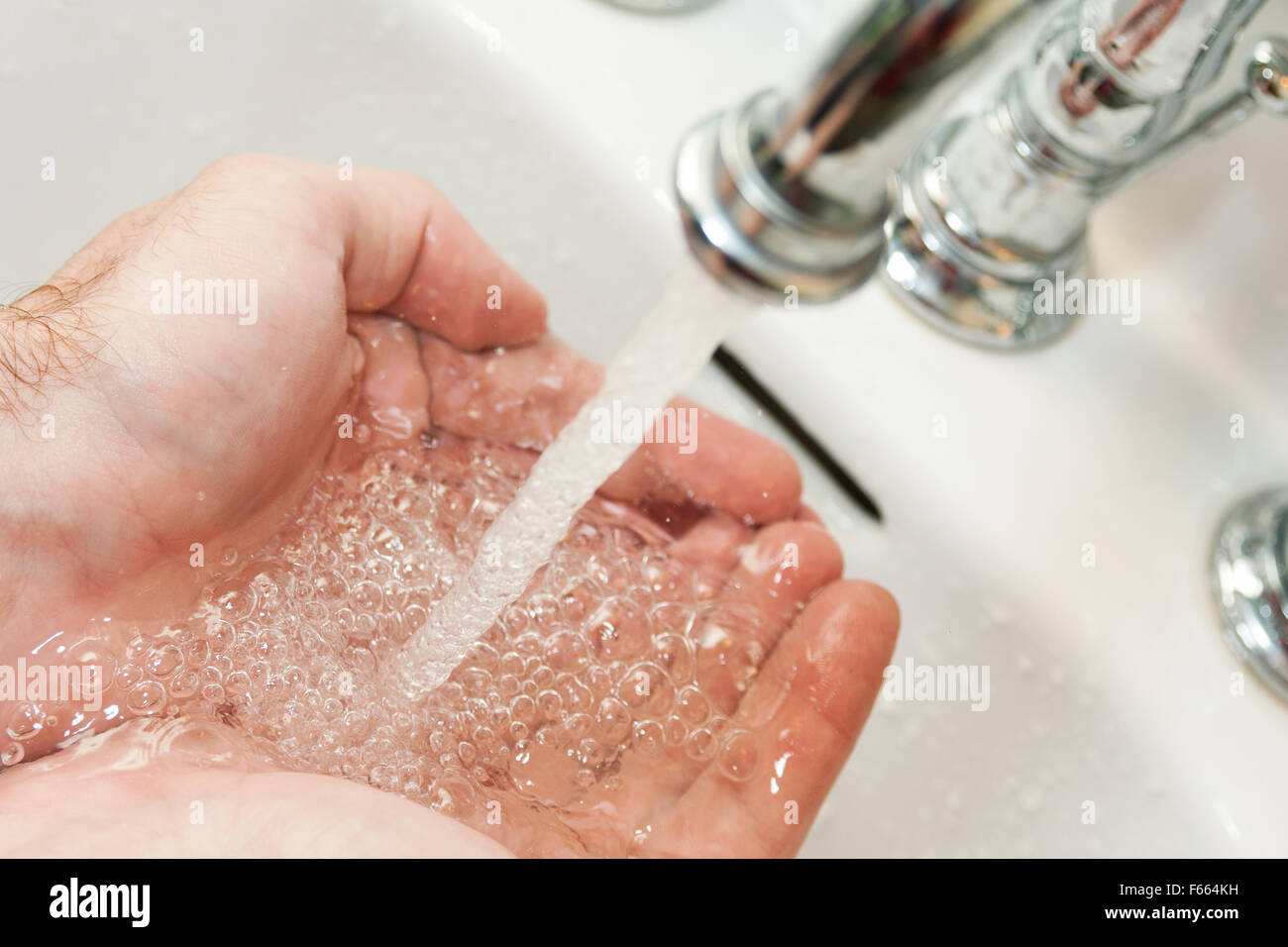 Close-up of human hands being washed under stream of pure water from ...
