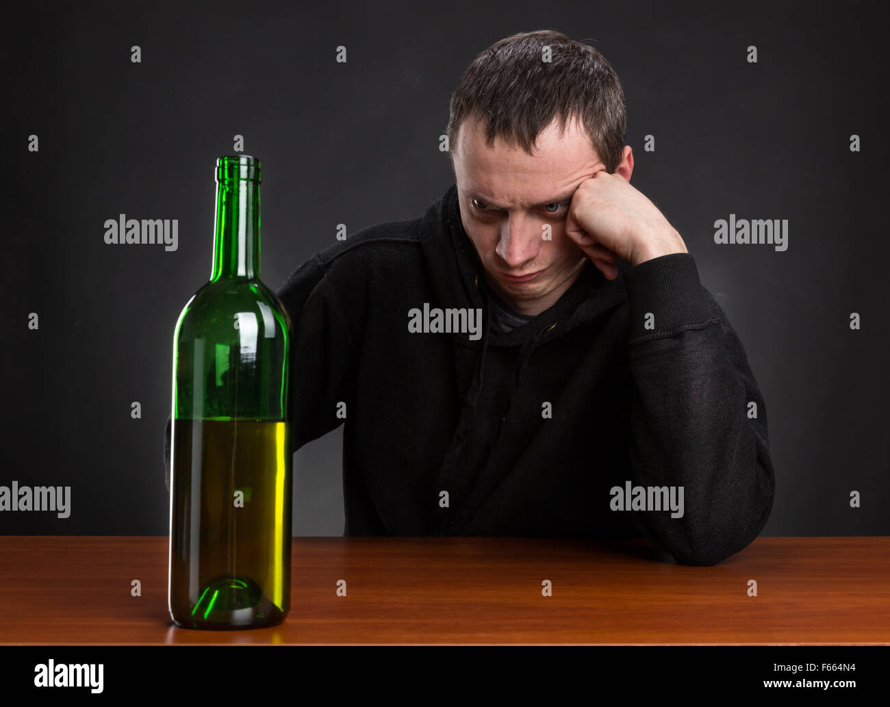 Sad man looks at the bottle of wine Stock Photo - Alamy