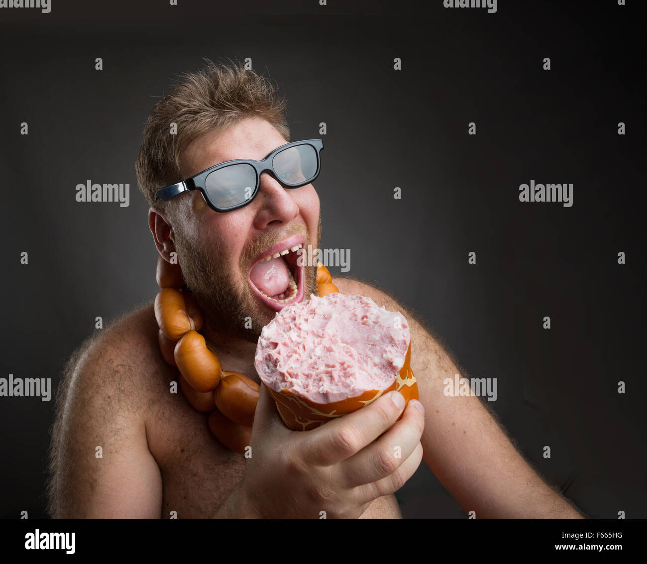 Hungry fat man with sausages round his neck eats a big wurst over grey ...