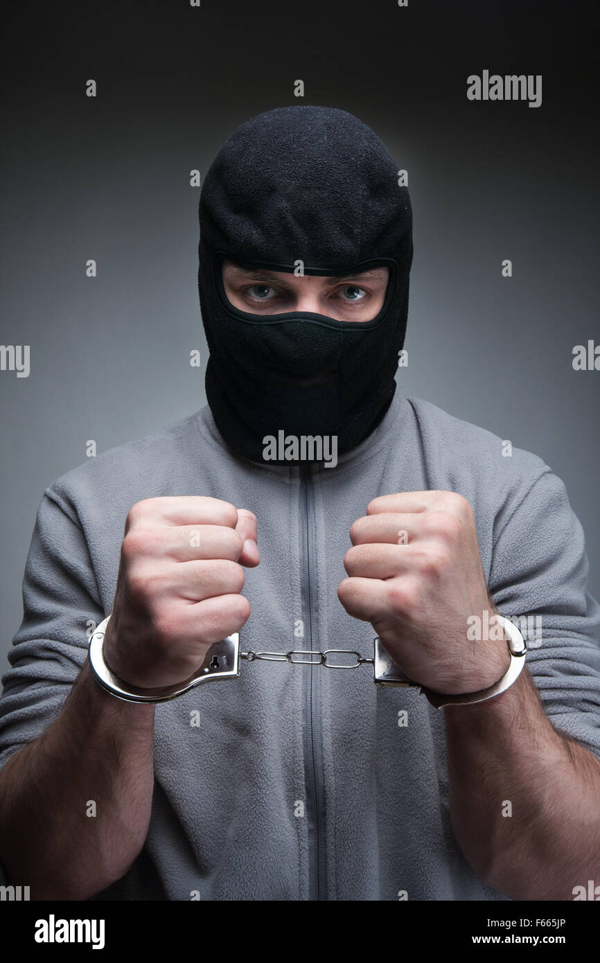 Criminal in black mask with handcuffs over grey Stock Photo - Alamy