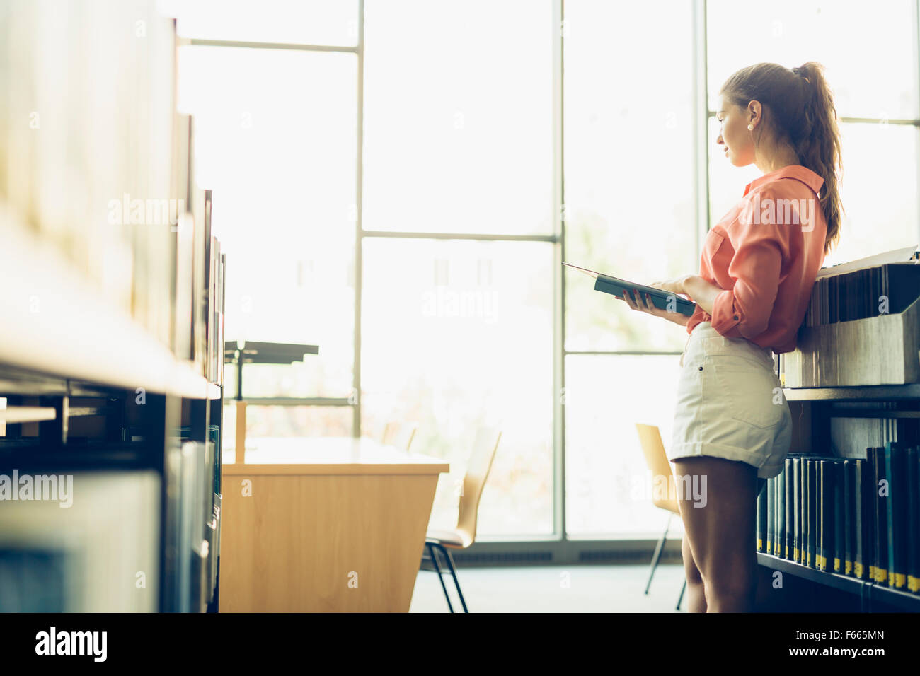 Beautiful woman reading a book in a library and thinking Stock Photo ...