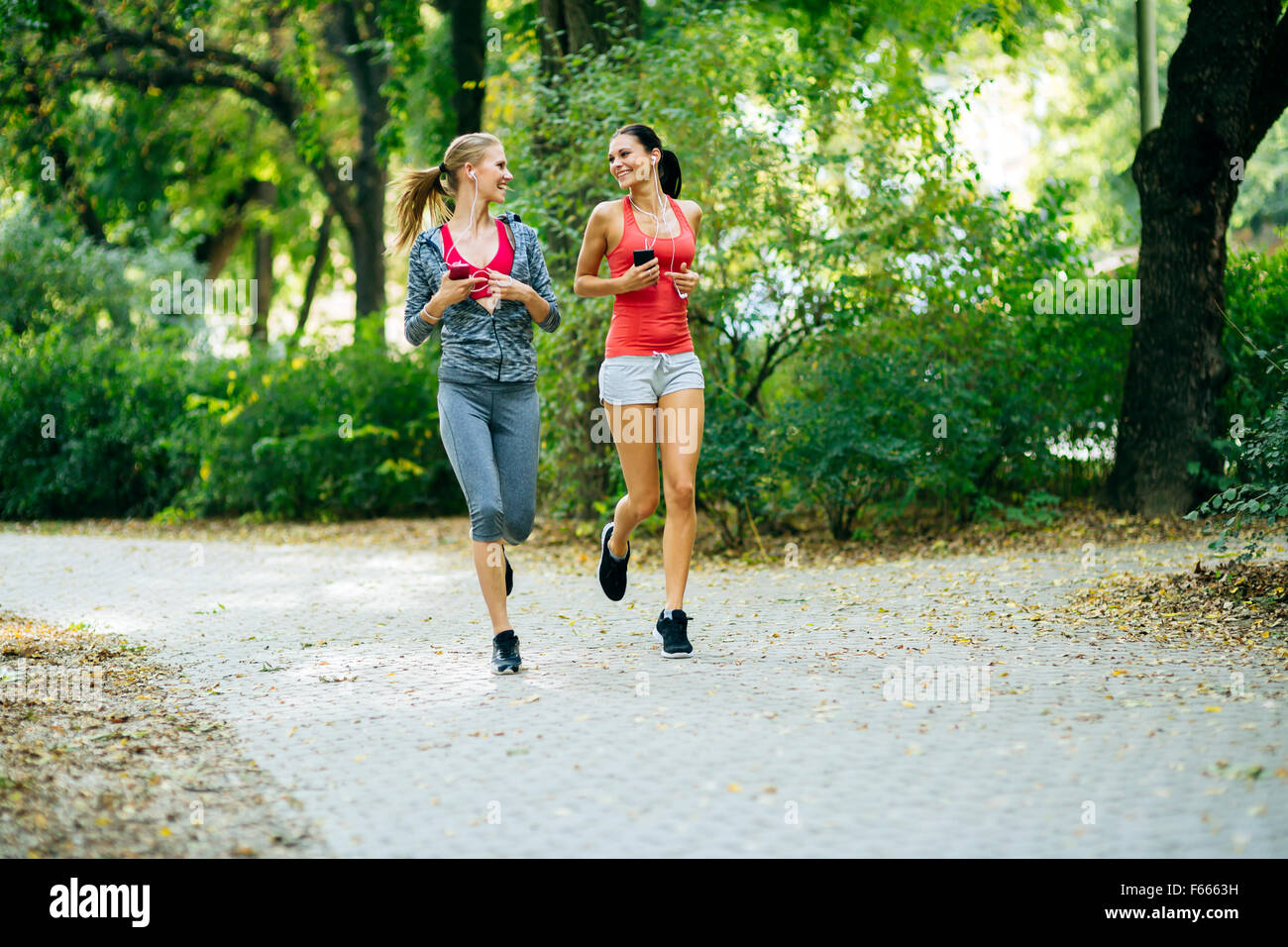 Energetic young women running outdoors in park to keep their bodies in ...