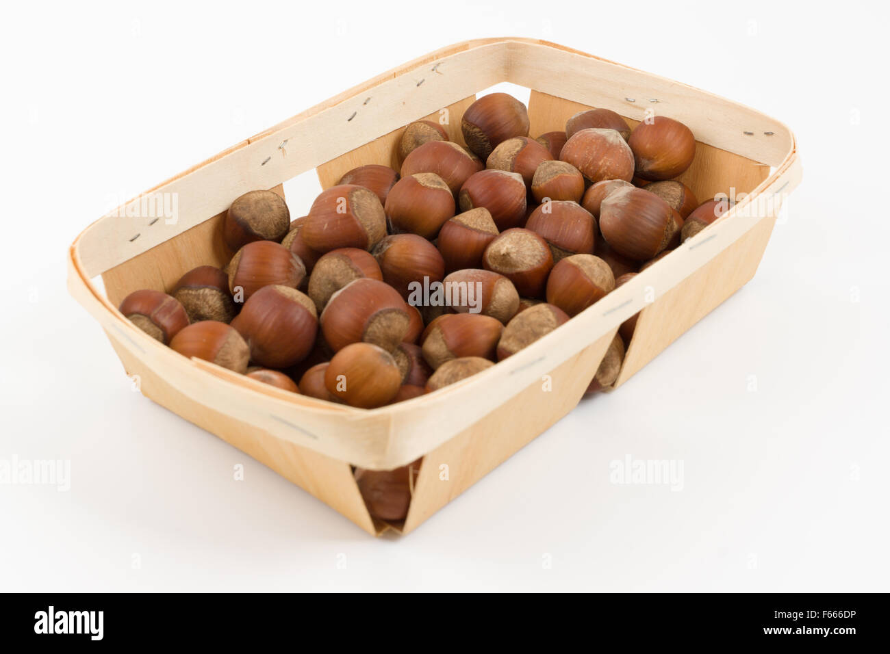 the wooden container is filled with hazelnut on a white background ...