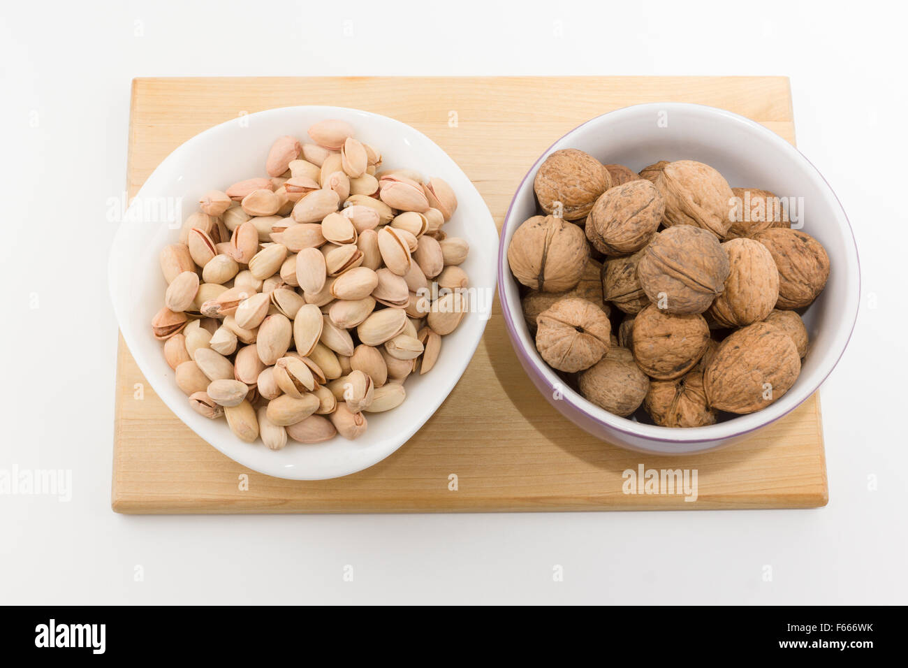 the platefuls of different nuts stand on a plate on a white background ...