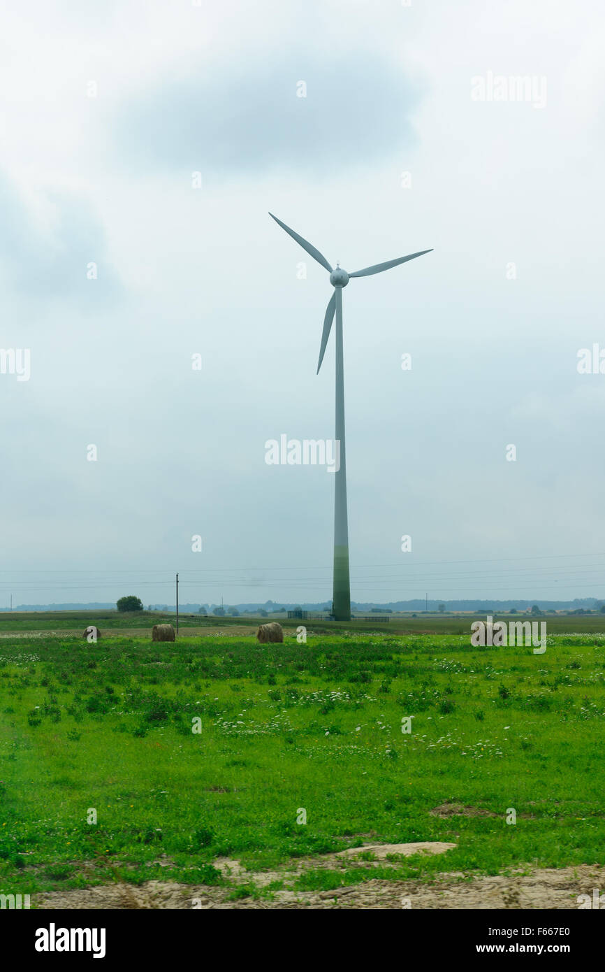 the wind-driven generator in the middle of a field serves for ...