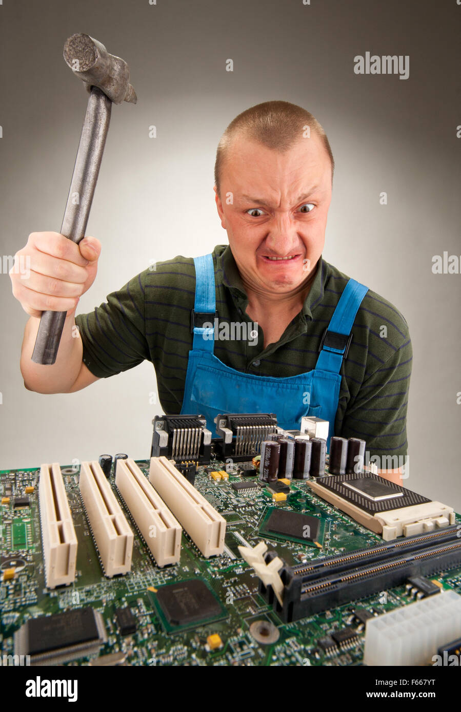 Mad IT worker repairing computer circuits by hammer Stock Photo - Alamy