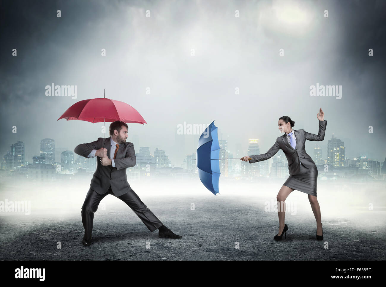 Business people fighting with umbrellas against cityscape in the night ...