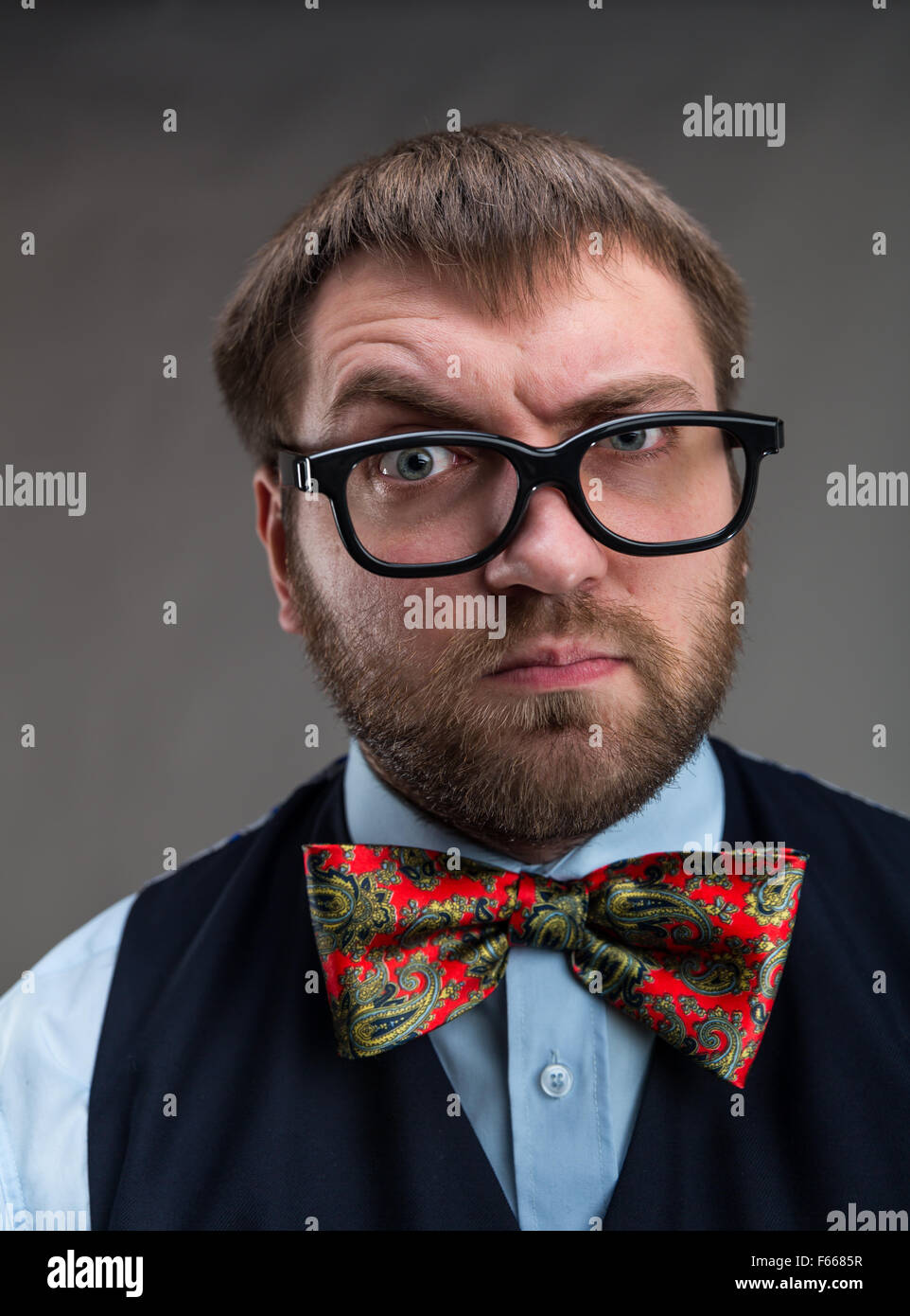 Strange suspicious-looking nerd in glasses looks at you over grey ...