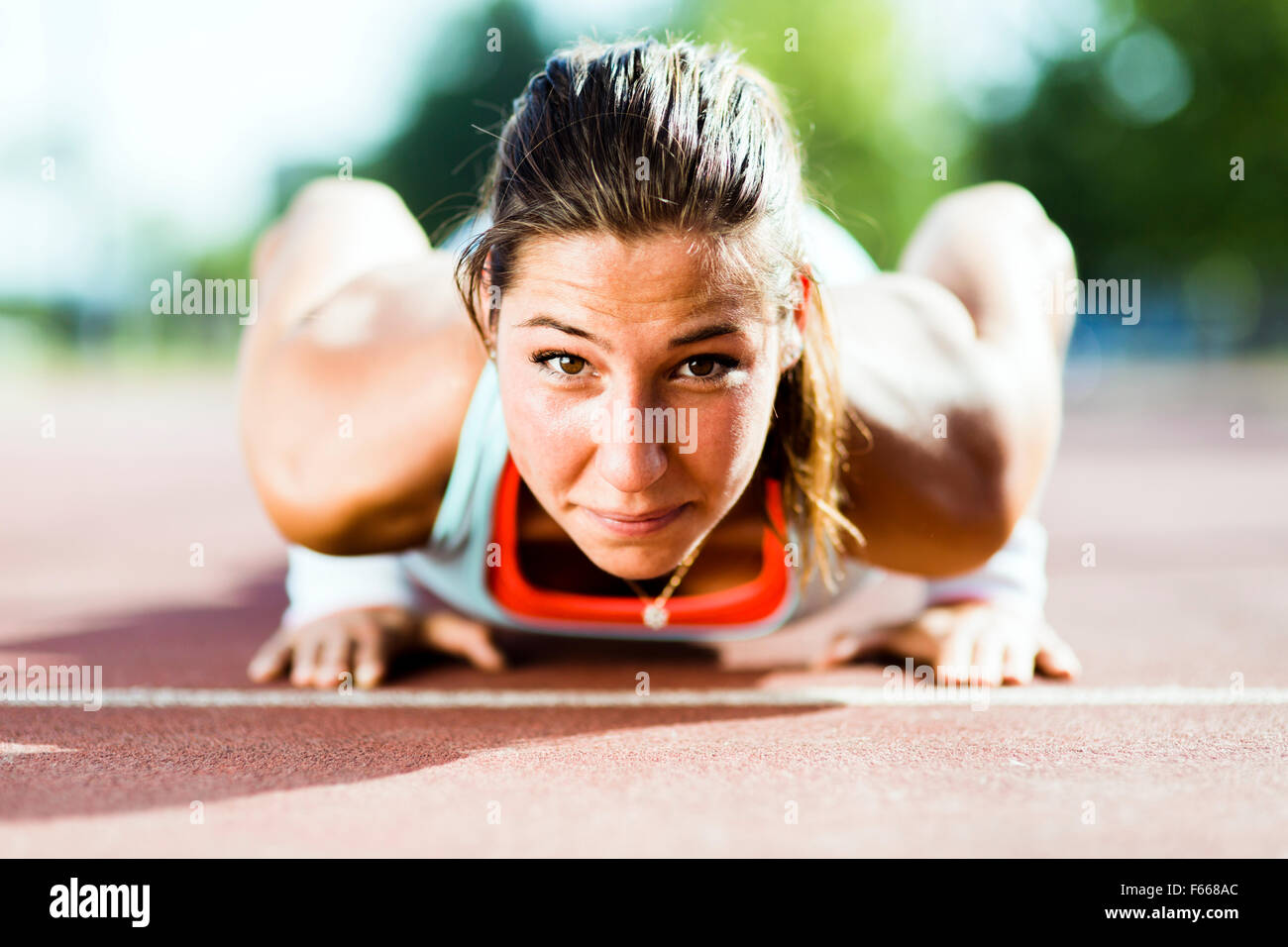 Focused young beautiful woman doing push-ups outdoors on a hot summer ...