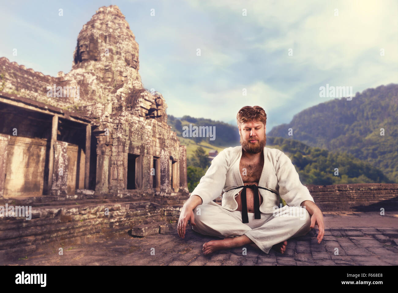 Fat karate fighter sits with crossed legs meditating Stock Photo - Alamy