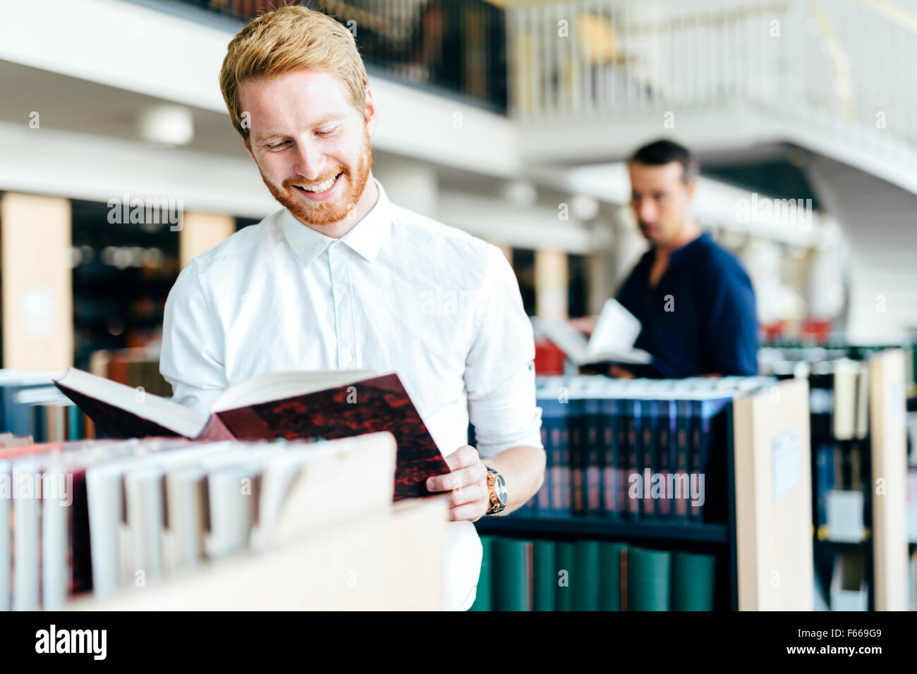 Handsome student reading a book in a beautiful library Stock Photo - Alamy