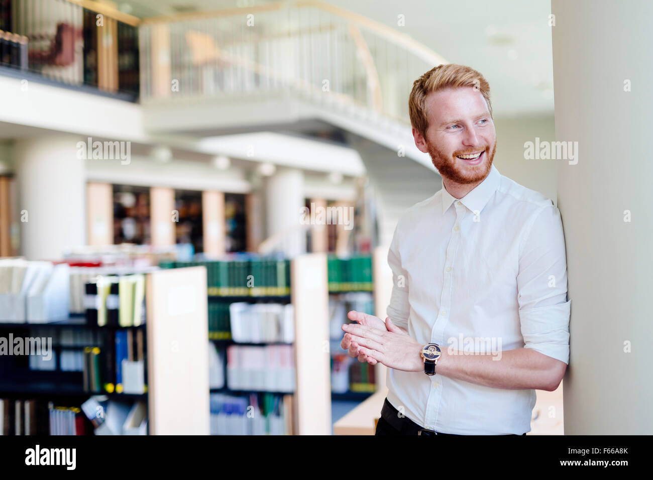 Handsome intelligent male student smiling in library Stock Photo - Alamy