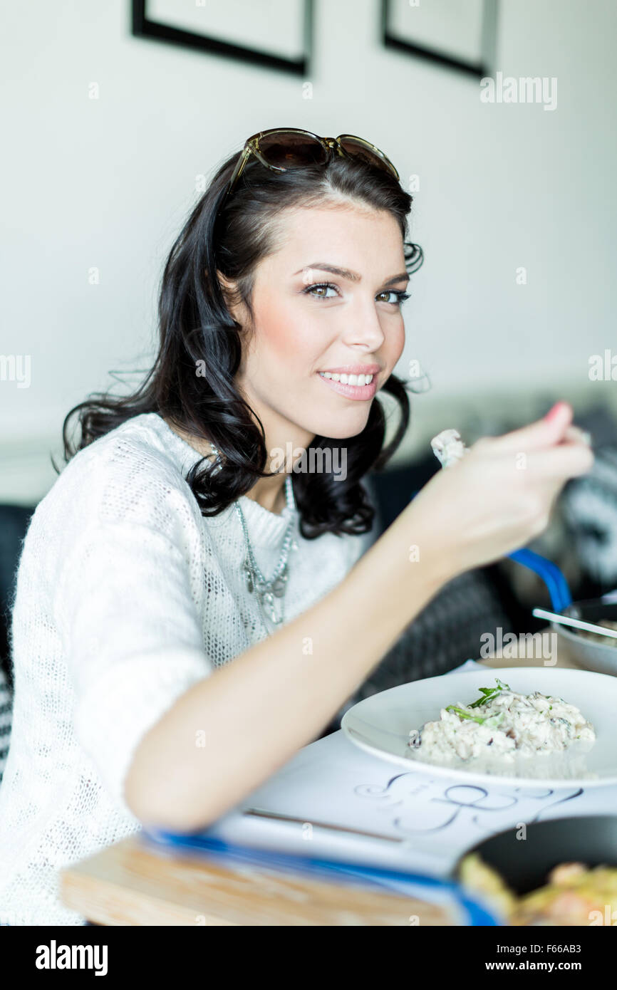 Beautiful young lady having a meal in a restaurant and about to take a ...