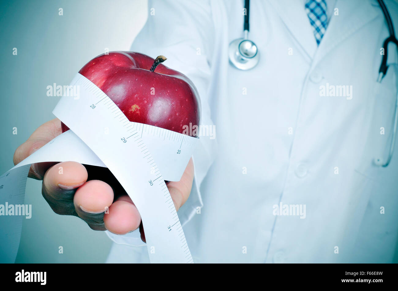 closeup of a caucasian doctor man with a red apple and a measuring tape ...
