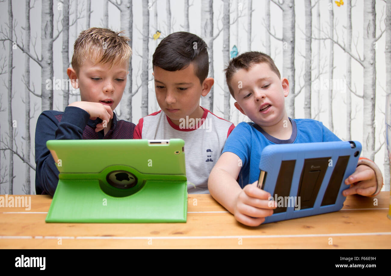 Three young boys playing games on tablets Stock Photo - Alamy