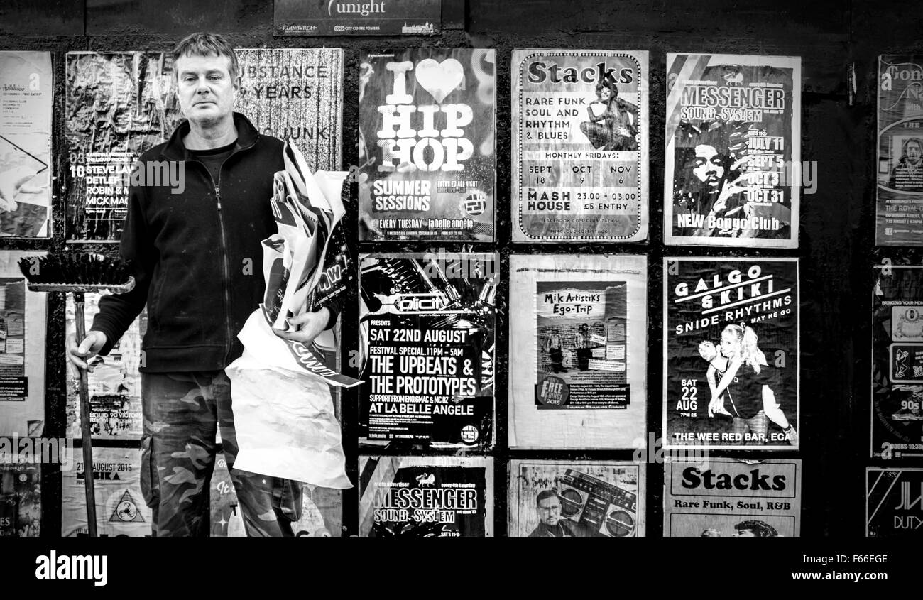 Man at work sticking up posters and advertisements for movies and bands ...