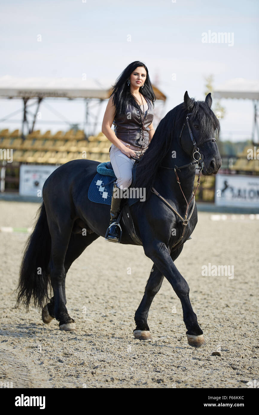 Beautiful young woman riding a horse on a hippodrome Stock Photo - Alamy