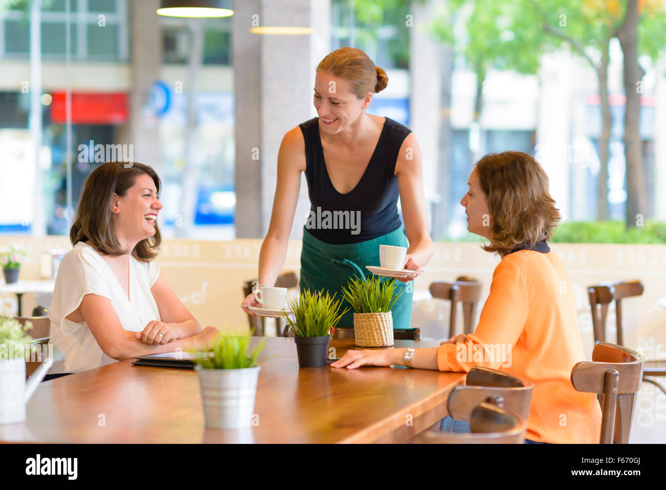Waitress serving two happy women in a restaurant Stock Photo - Alamy
