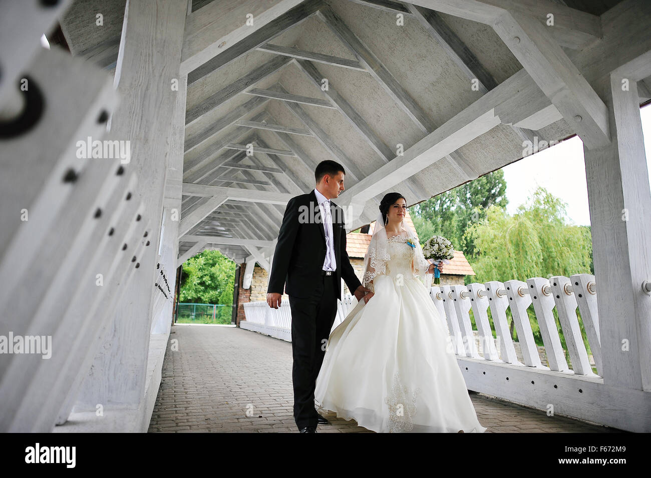 young cute wedding couple walking at the covered wooden bridge Stock ...