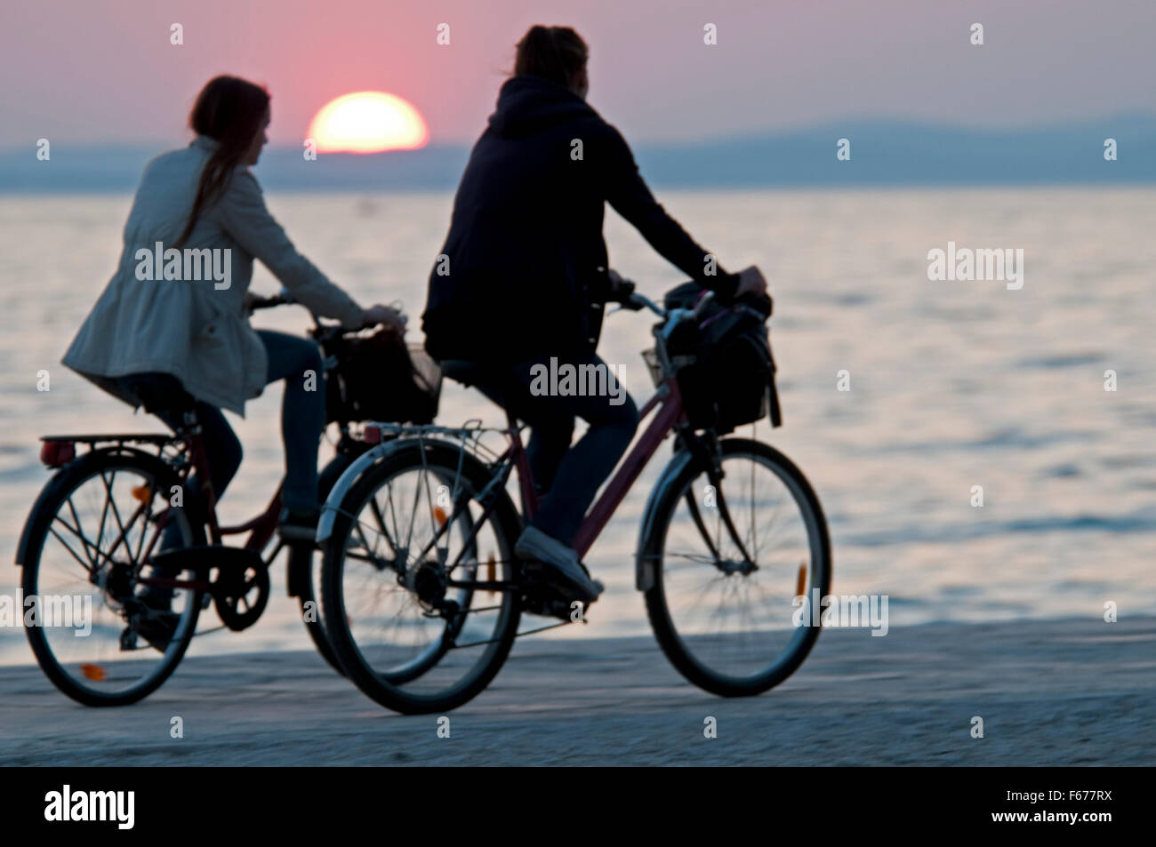 cycle with sunset on the horizon above sea Stock Photo - Alamy