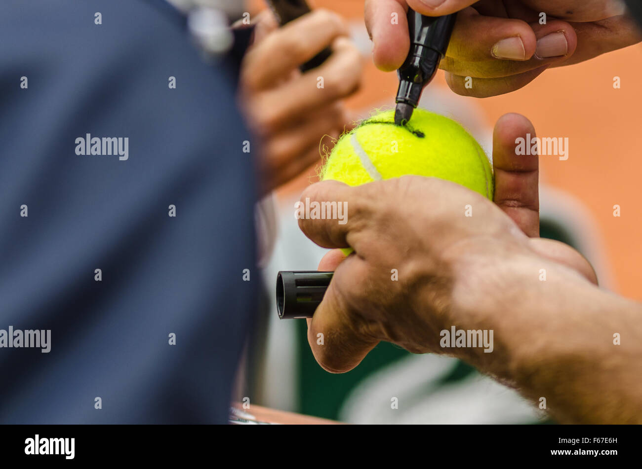 Tennis player signs autograph on a tennis ball after win, closeup photo ...