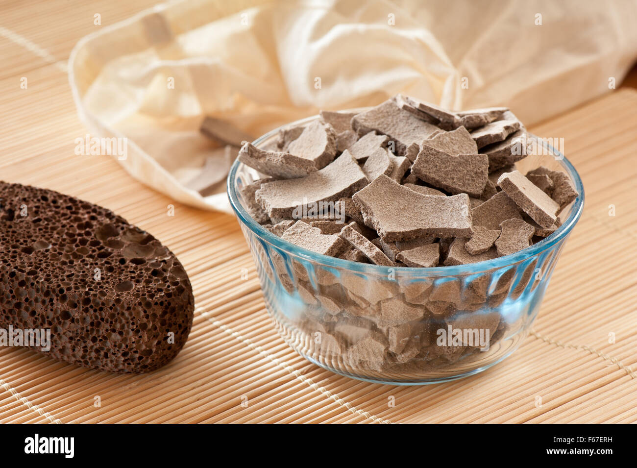 Ghassoul lava clay and pumice, dried chips in glass bowl and natural ...