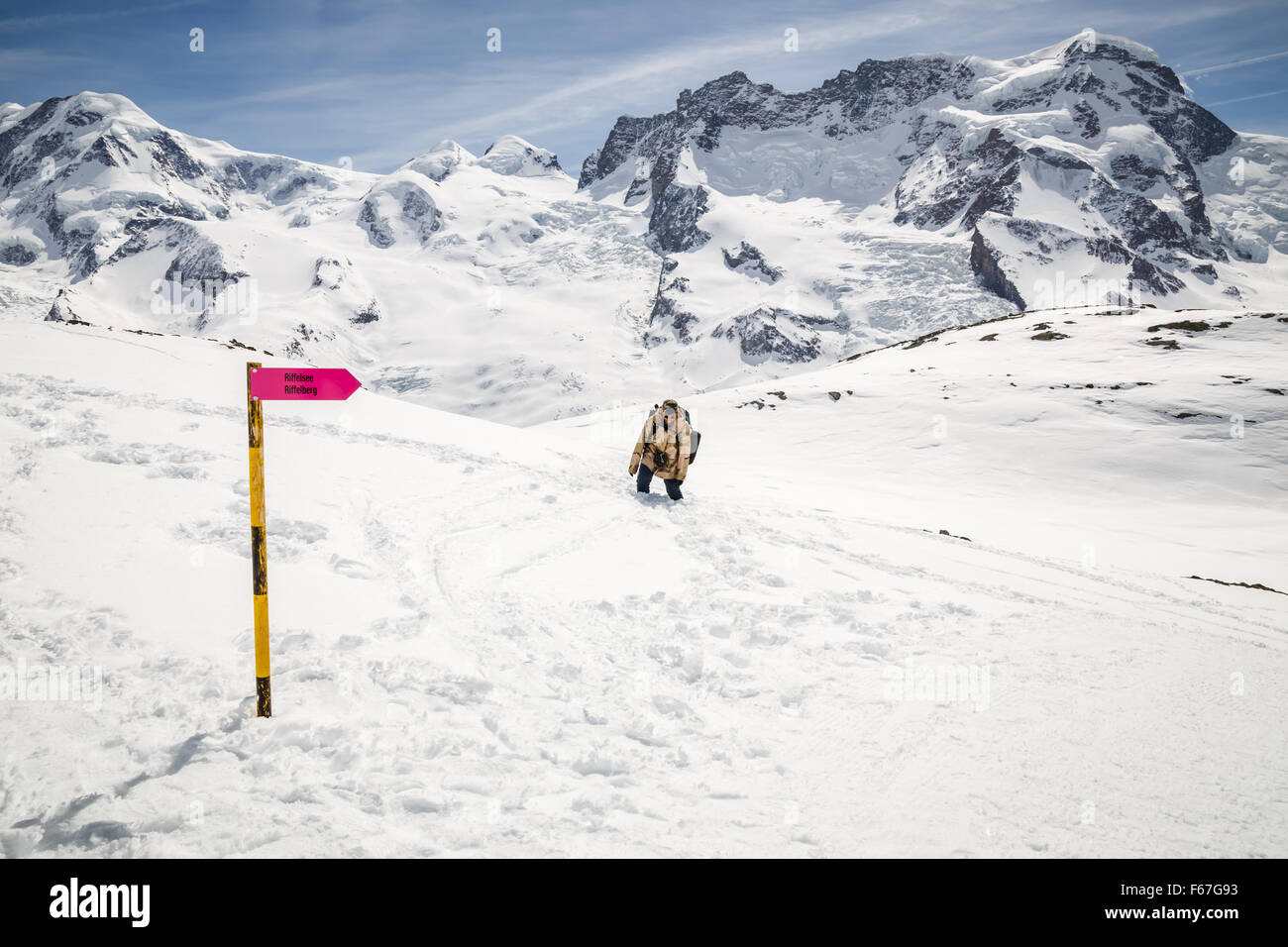 Man drop into the snow behind direction guide post in the background of ...