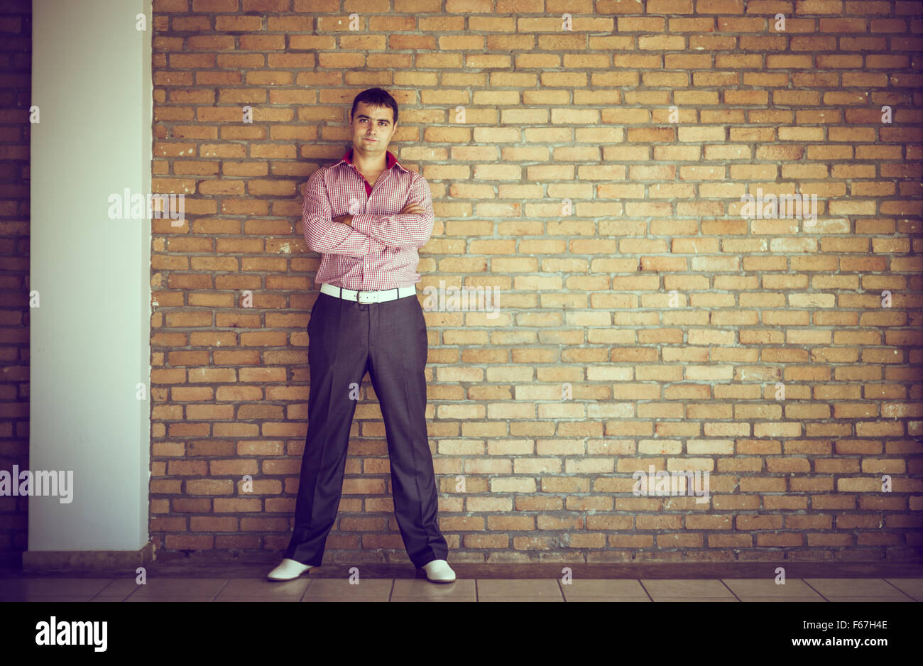 the portrait of young man posing along against brick wall Stock Photo ...