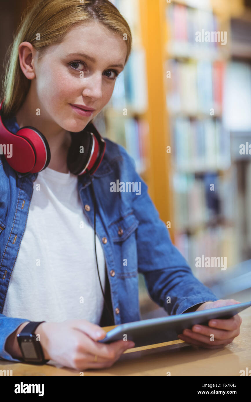 Pretty student with headphones using tablet in library Stock Photo - Alamy