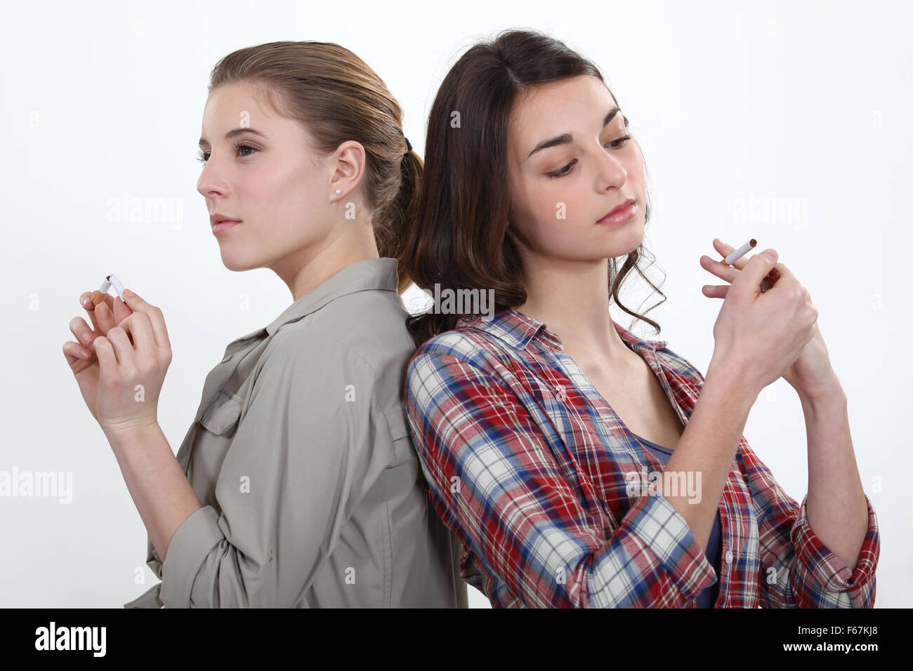 Girl lighting a cigarette as another snaps one in half Stock Photo - Alamy