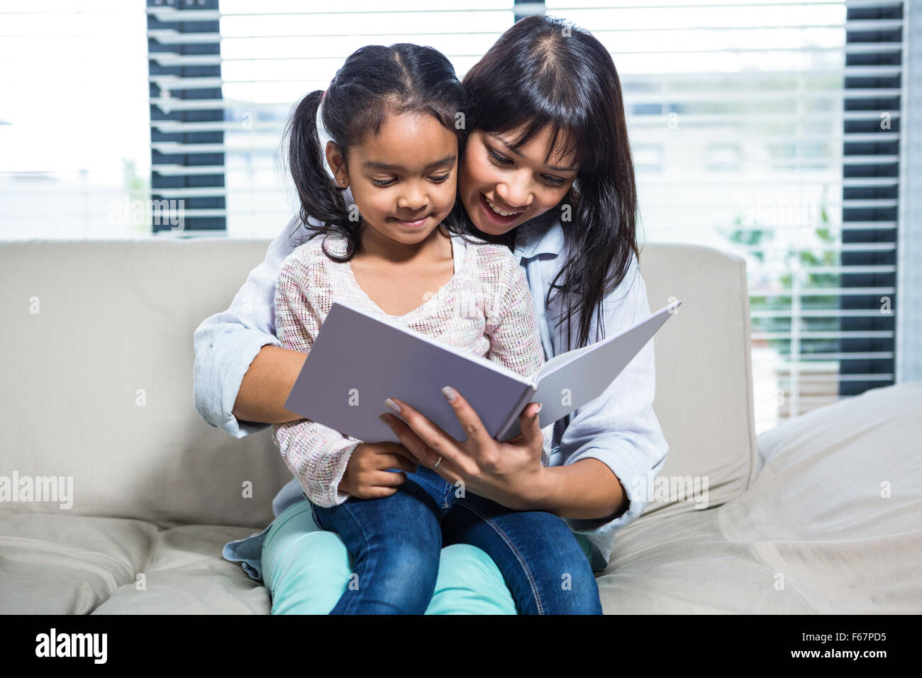 Happy mother reading book with her daughter Stock Photo - Alamy