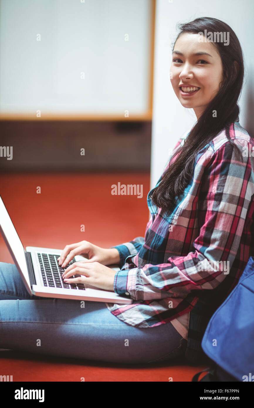 Smiling student sitting on the floor and using laptop Stock Photo - Alamy