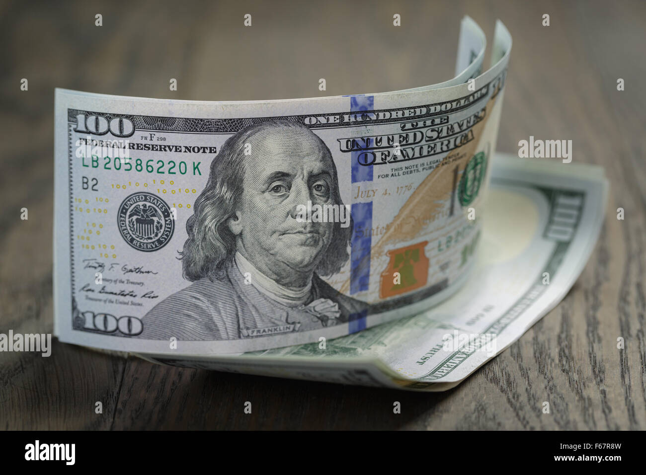 hundred dollar bills on wood table Stock Photo - Alamy