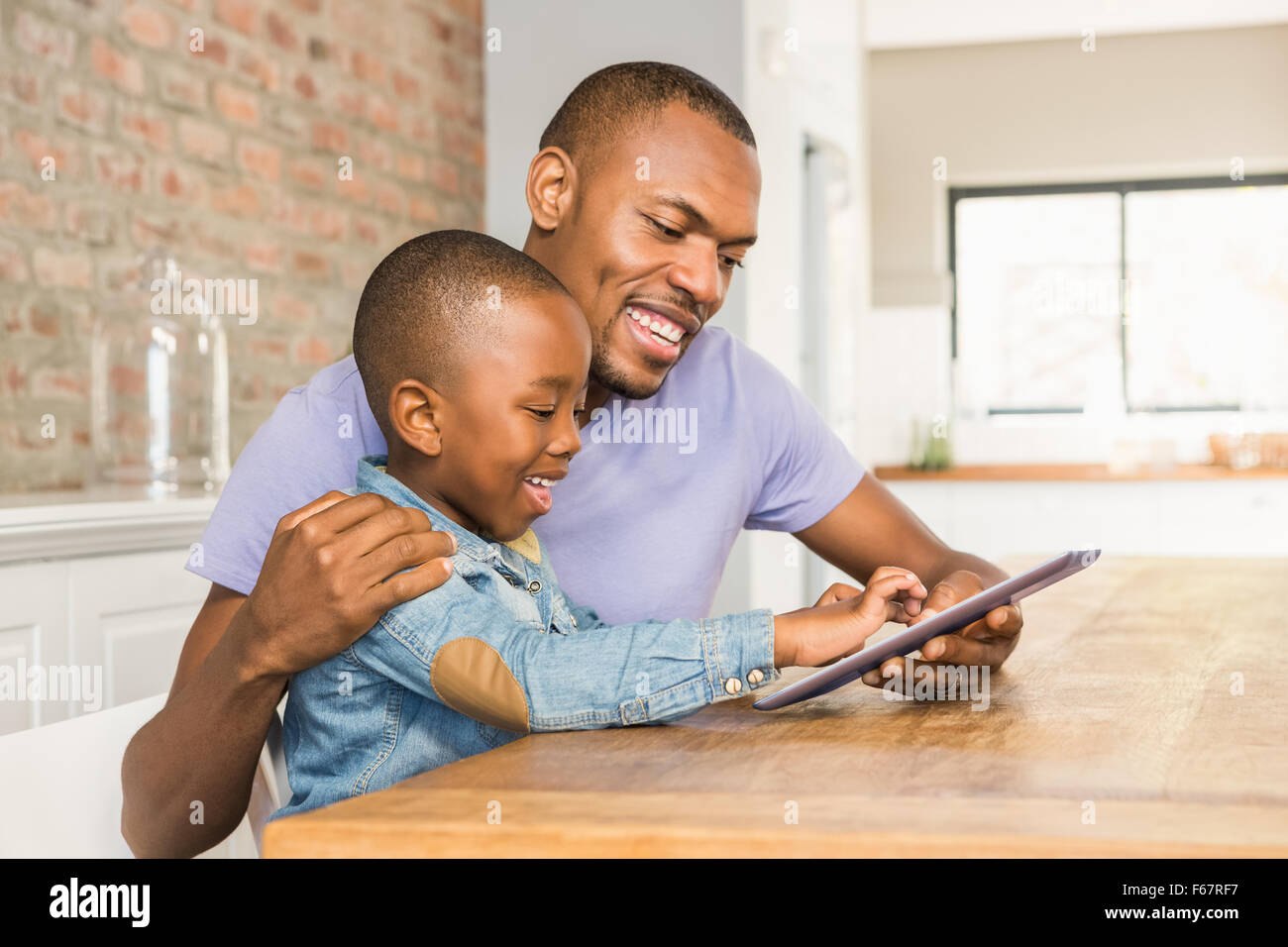Cute son using tablet at desk with father Stock Photo - Alamy