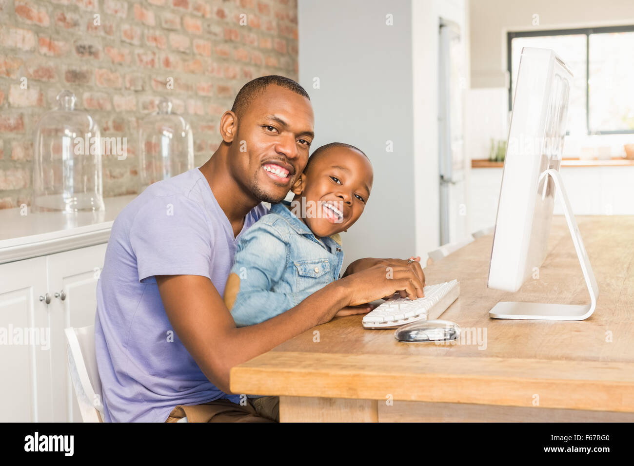 Cute son using laptop at desk with father Stock Photo - Alamy
