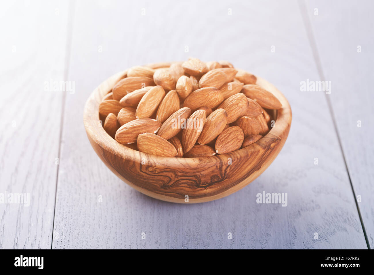 roasted almonds in wood bowl on blue wooden table Stock Photo - Alamy